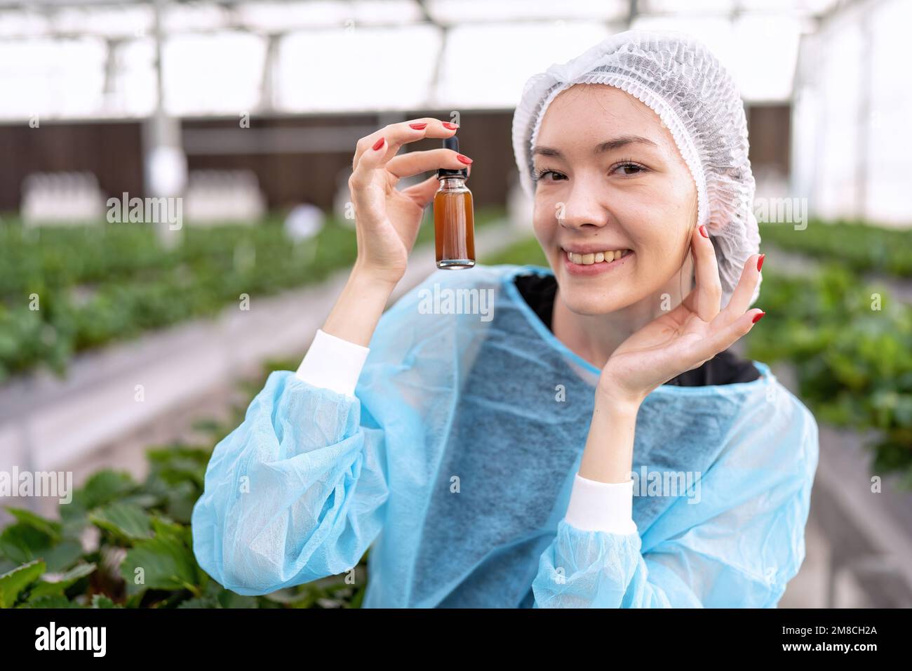 Doctor nutritionist in greenhouse farming proudly showing bottle of ...