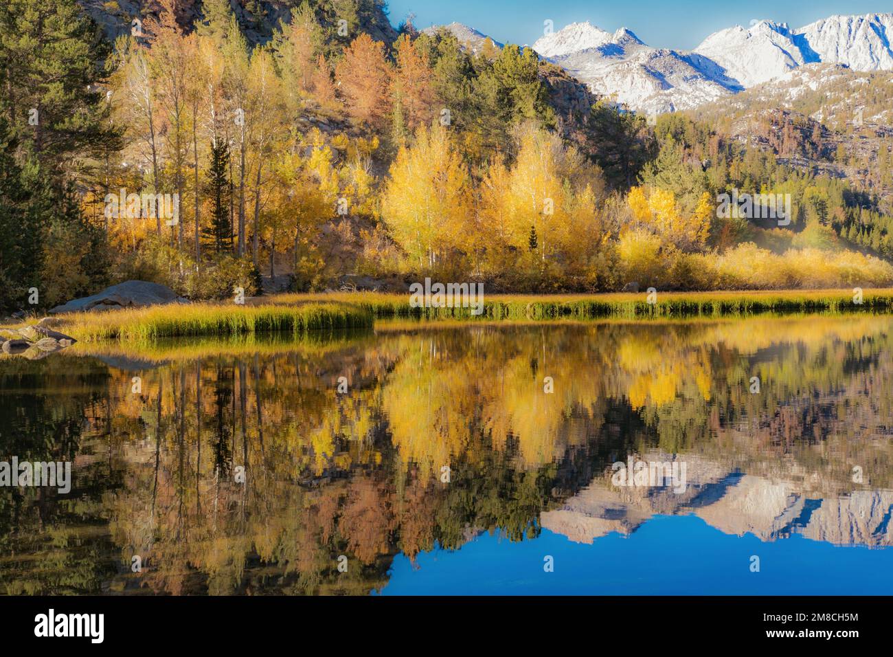 The beautiful view of the smooth lake reflecting the autumn trees on ...