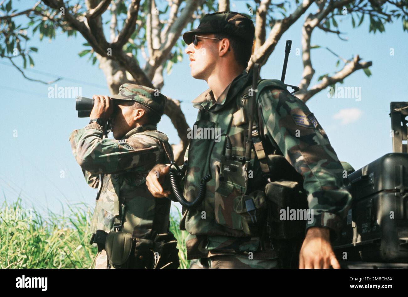 Two airmen scan the surrounding area from a hilltop observation post. A ...