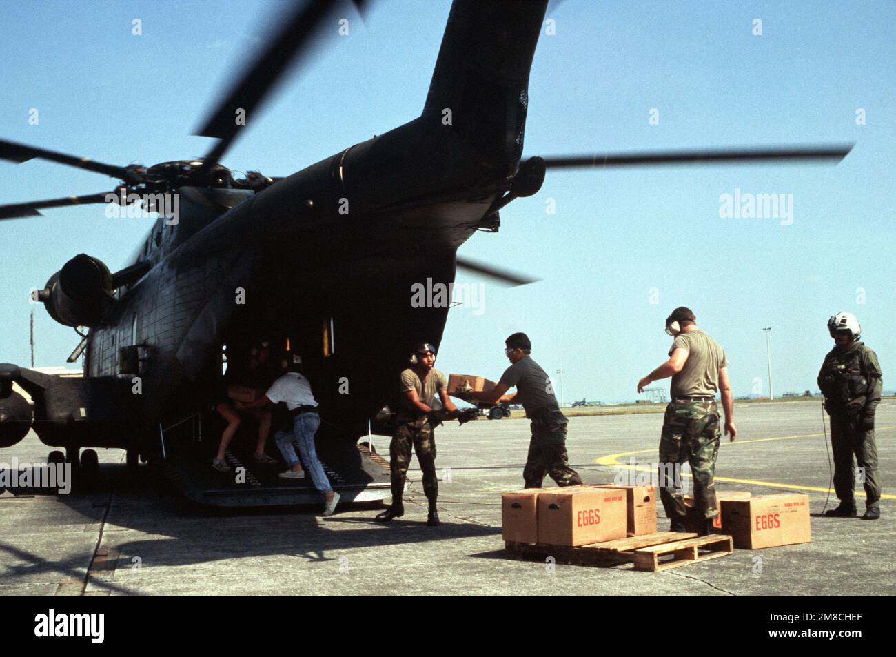 A flight crewman watches as airmen load supplies aboard a Marine Corps ...