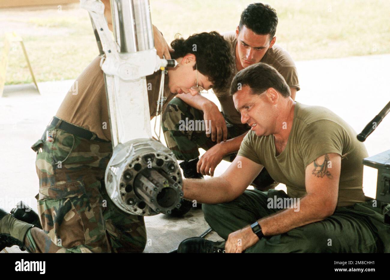 Three maintenance crewmen repair a set of main landing gear brakes on a ...