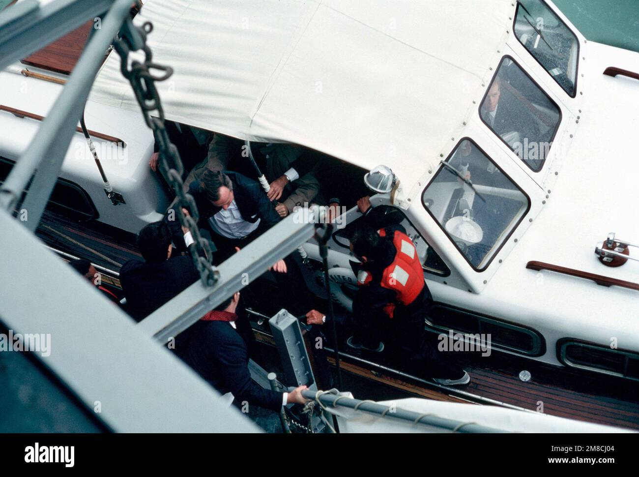 President George H.W. Bush is helped off of a launch onto the guided ...