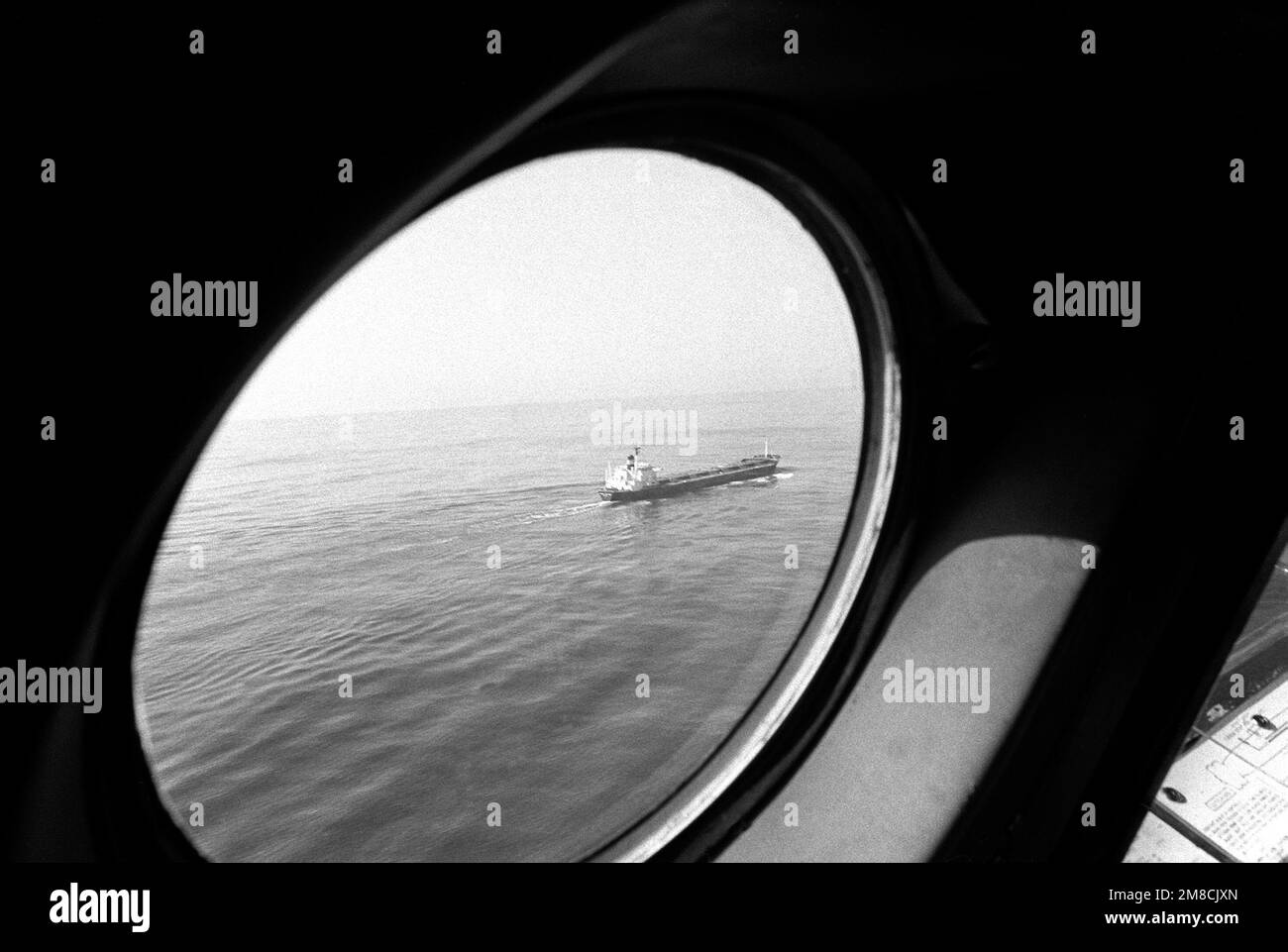 A merchant ship is seen through the porthole of a Naval Air Reserve ...