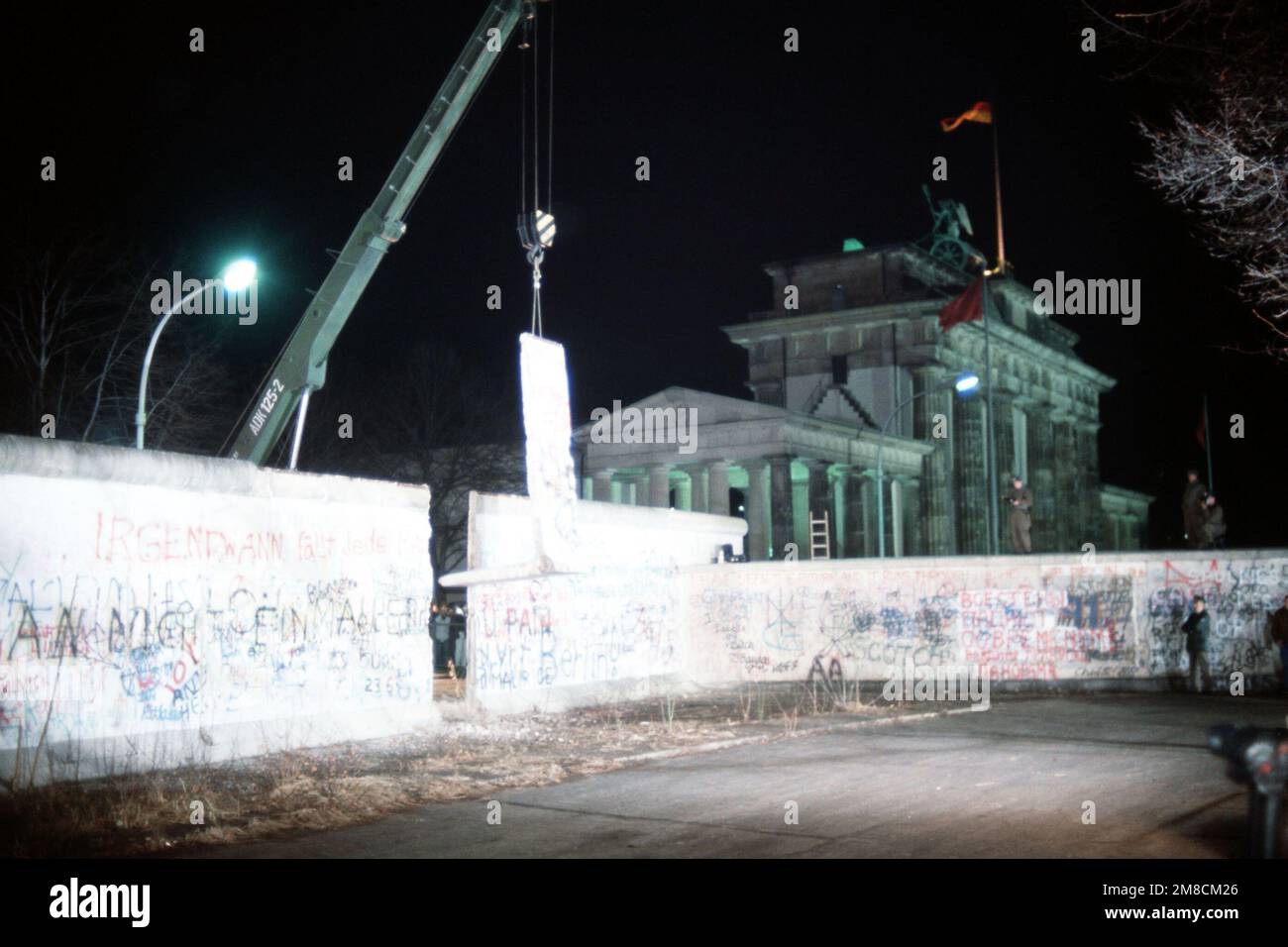 East German guards take photographs as a crane removes a section of the ...