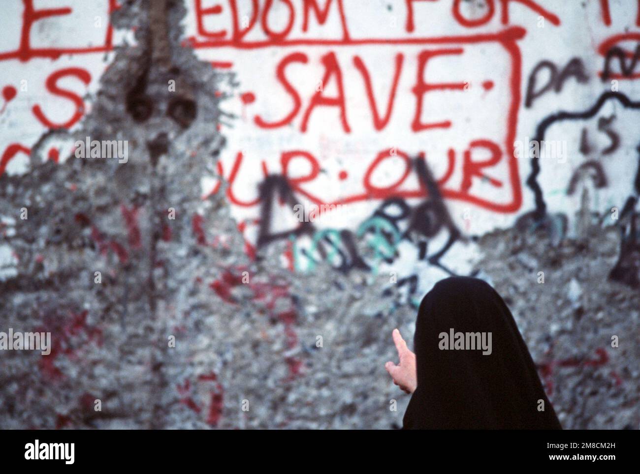 A nun studies the graffiti on a section of the Berlin Wall. Base ...
