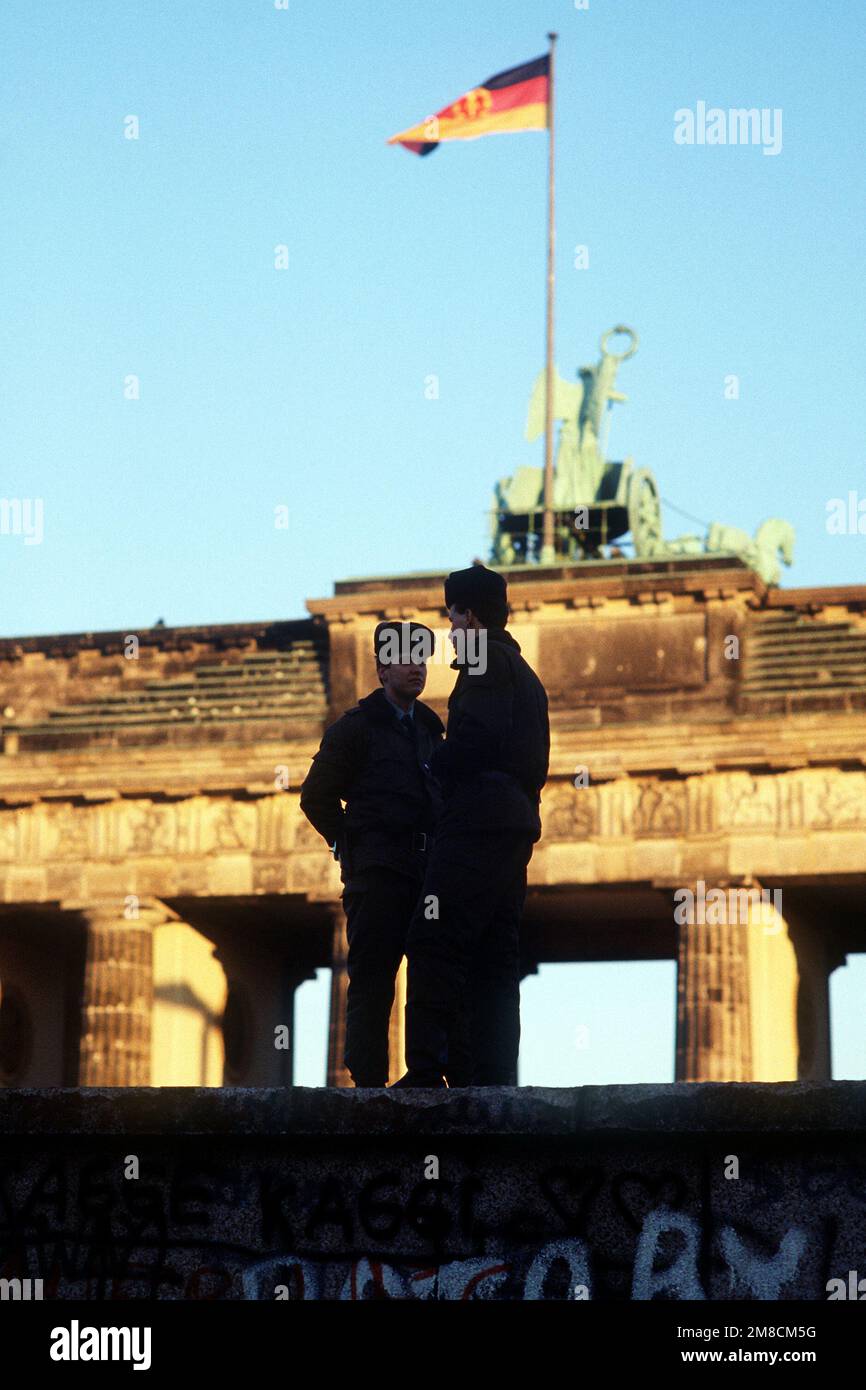 East German guards stand atop the Berlin Wall beside the Brandenburg ...
