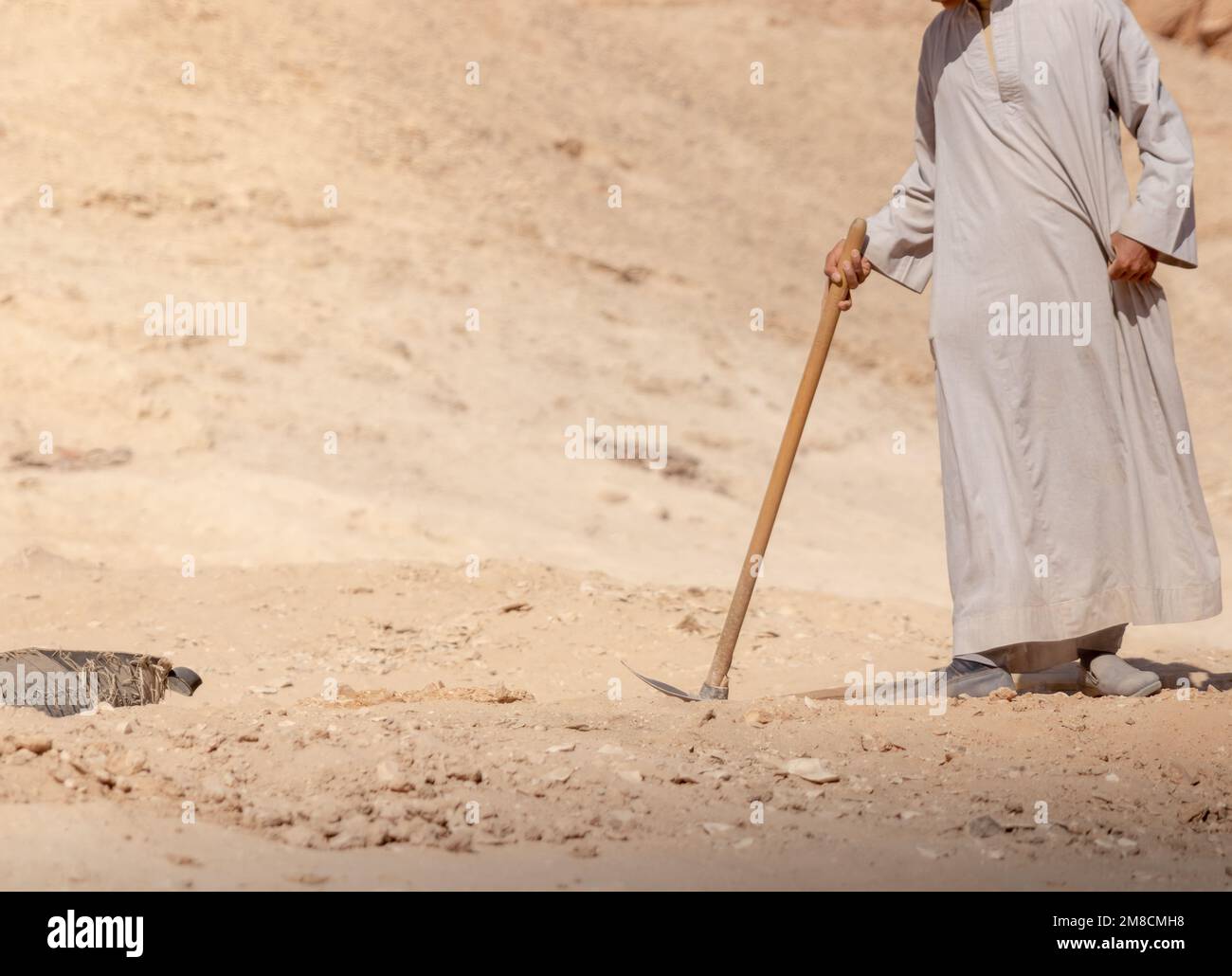 Unrecognizable hard working arab man with djellaba using shovel for ...