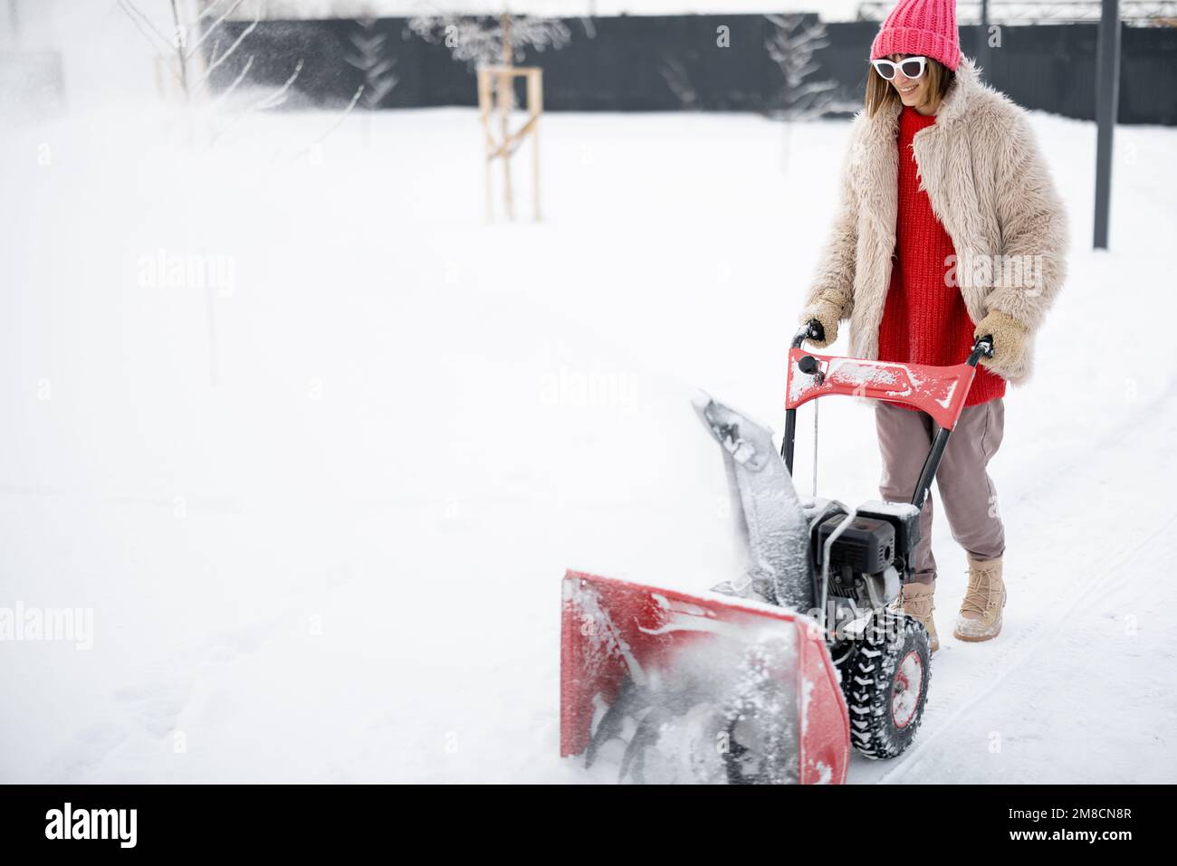 Woman removes snow from pathway with a snow thrower machine Stock Photo ...