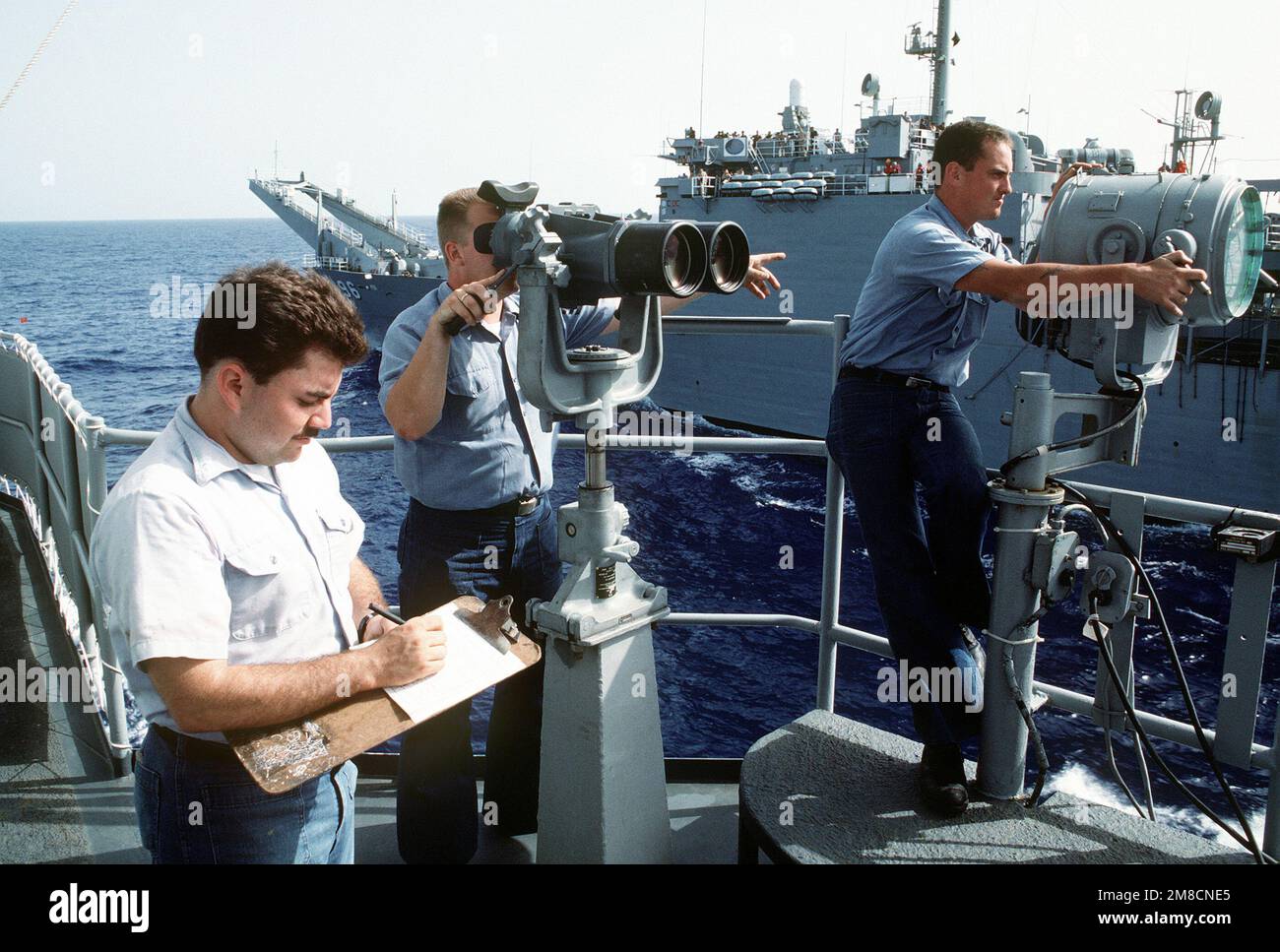 A signalman reads searchlight signals from another task force ship ...