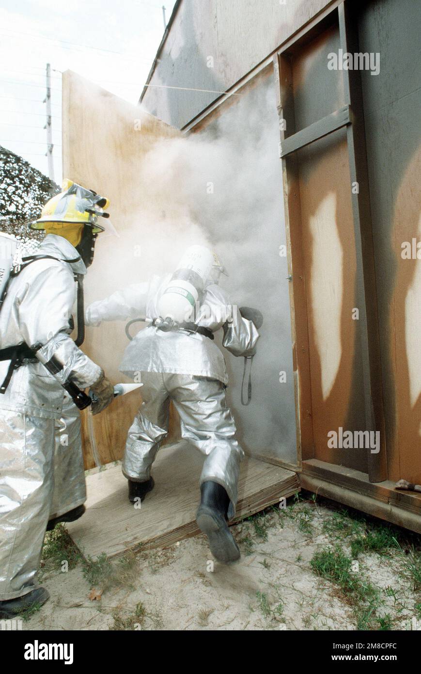 Participants wearing proximity suits enter a smoke-filled building as ...
