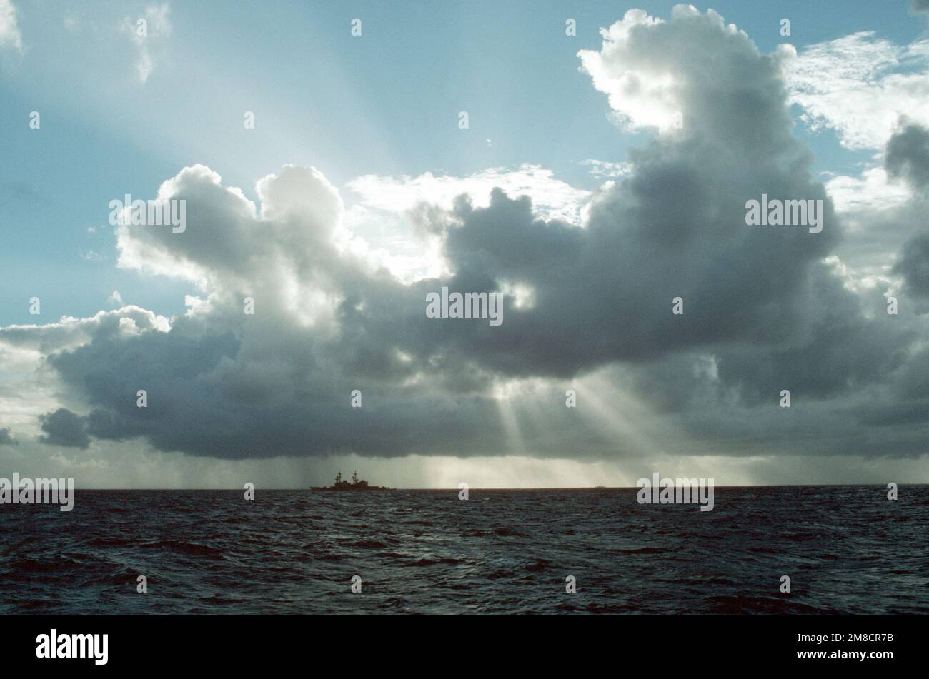 Sunlight silhouettes a US Navy ship on the horizon during FLEET EX-1-90 ...