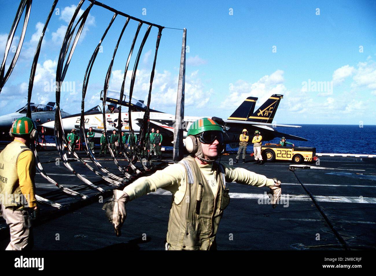 A catapult and arresting gear officer signals across the flight deck of ...