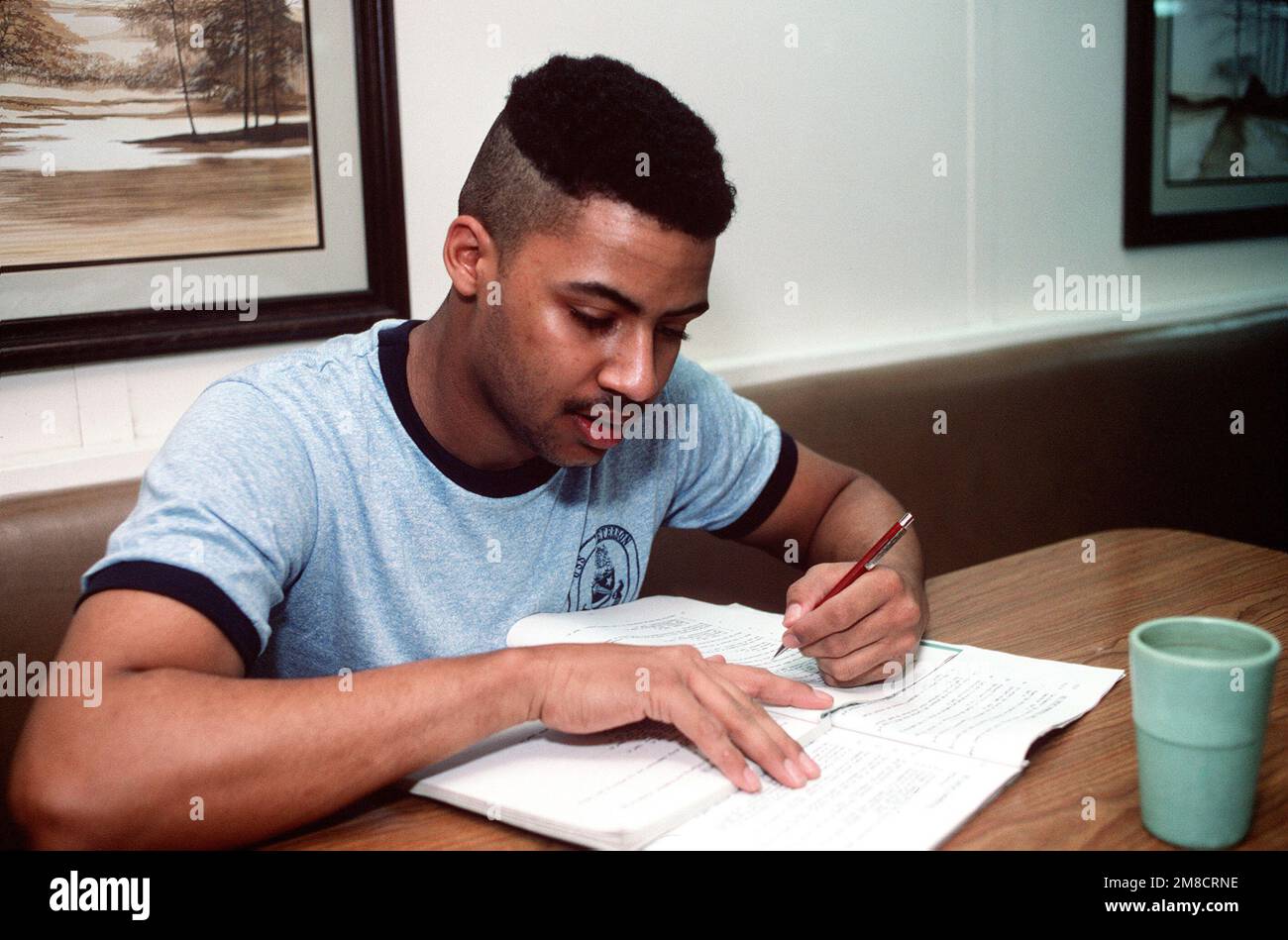 A crew member aboard the destroyer USS PETERSON (DD-969) studies for ...