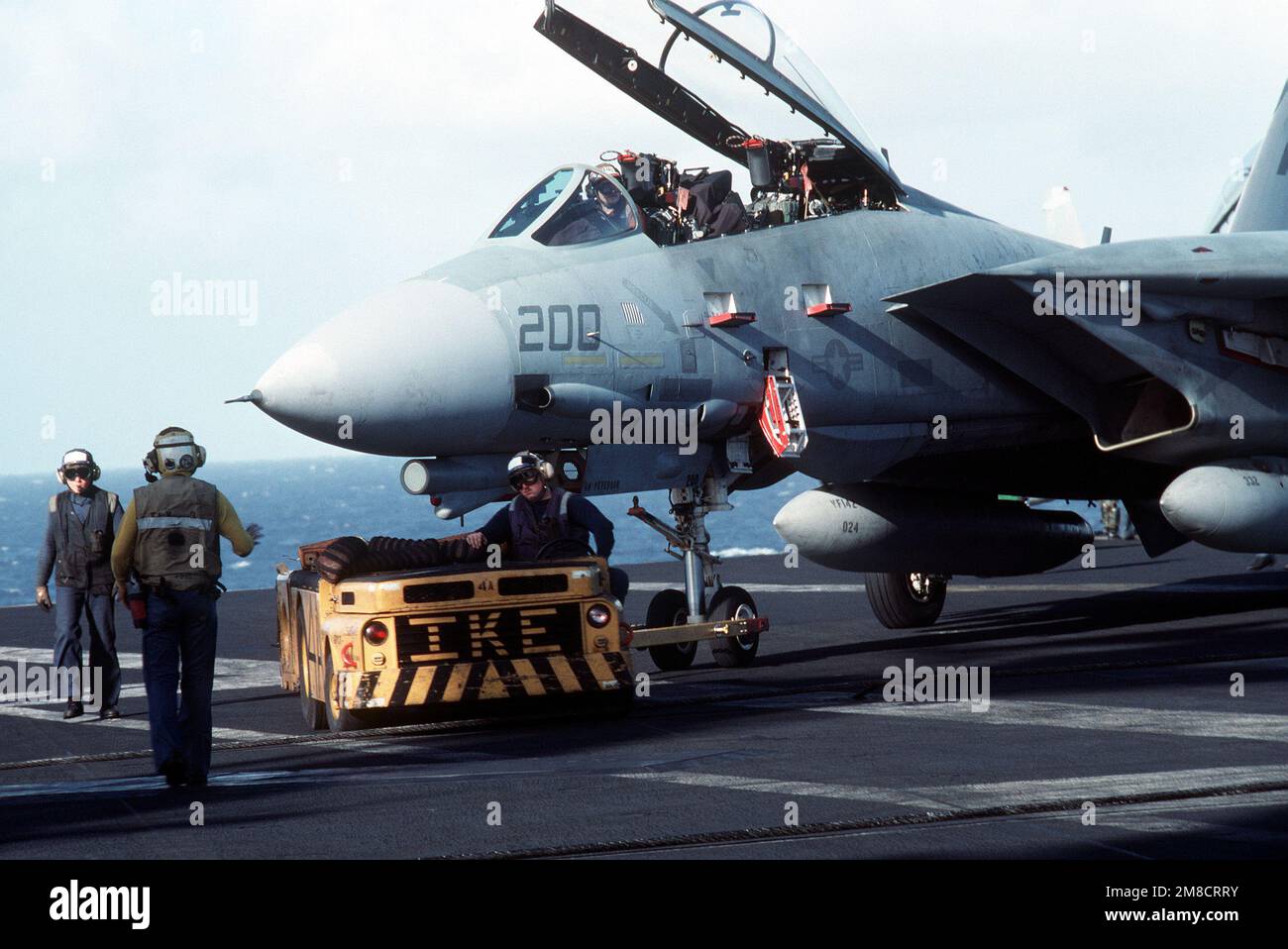 Flight deck personnel prepare to use an MD-3A tow tractor to tow an F ...