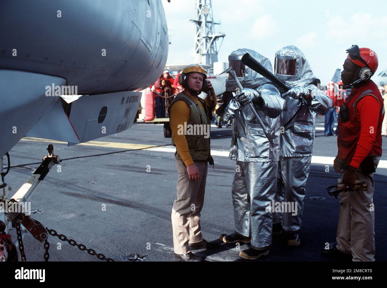 An air boss briefs firefighters in proximity suits who are ...