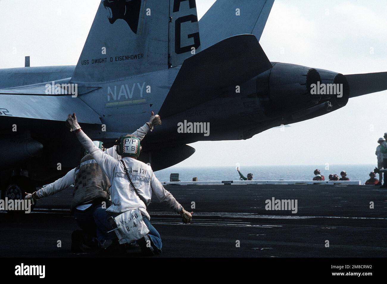 Flight deck crew members signal for the launch of an F/A-18A Hornet ...