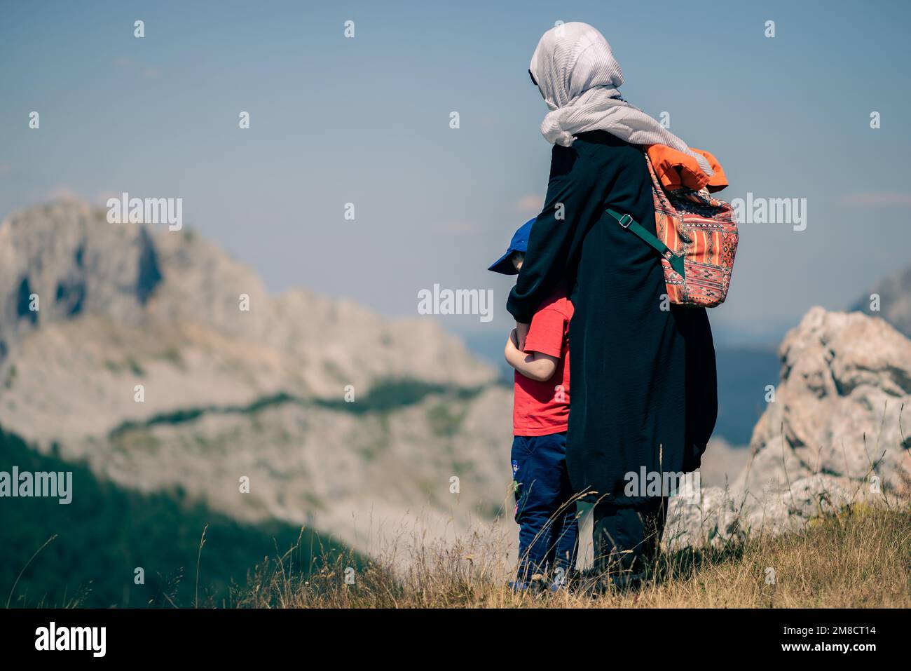 A child and his mother standing in in the wilderness and looking into ...