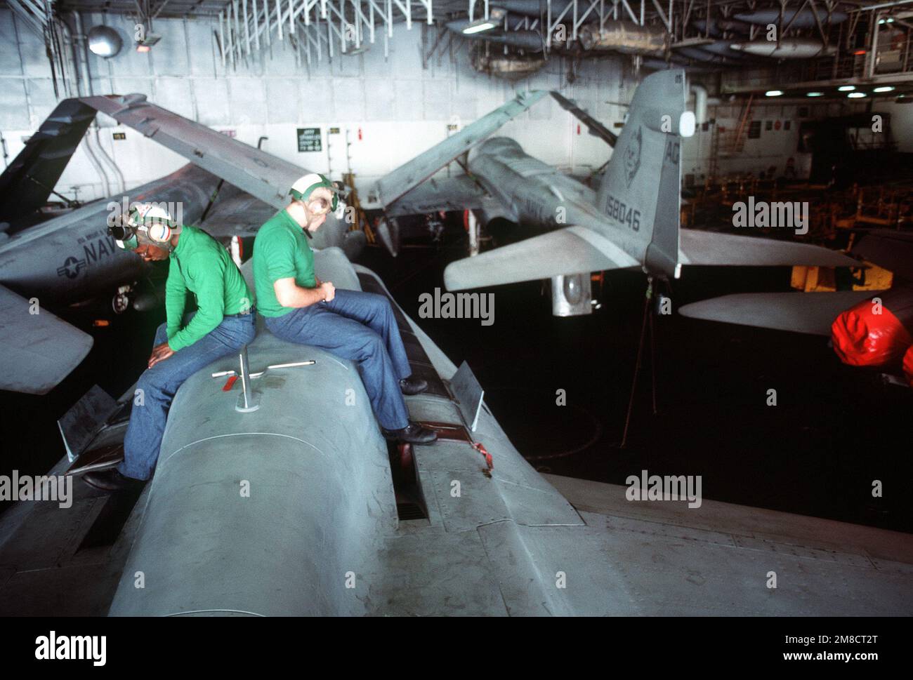 Crew members work on the fuselage of an F/A-18A Hornet aircraft in the ...
