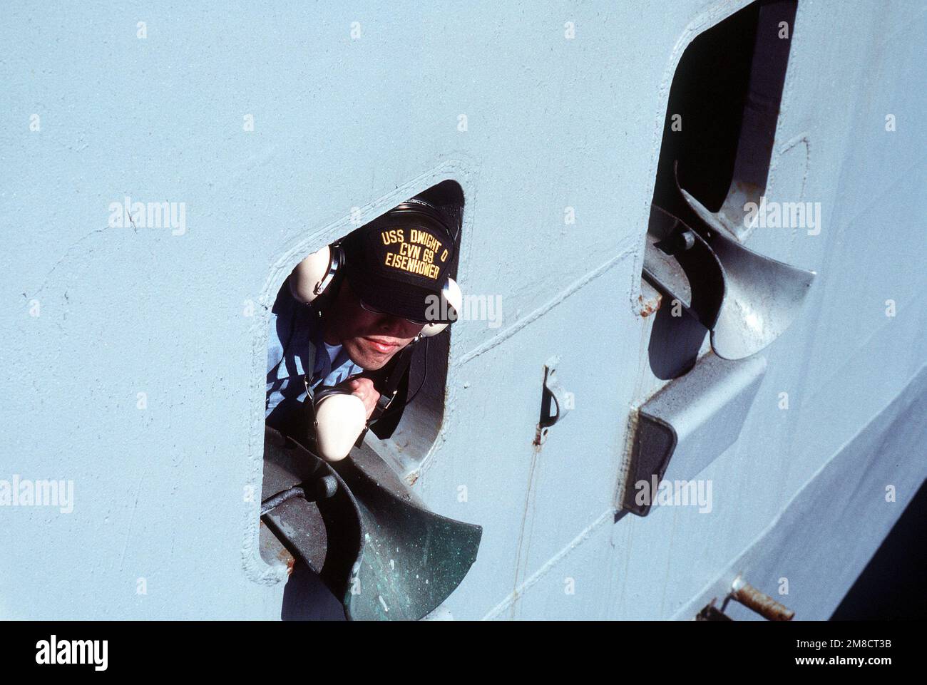 A sailor stands watch at a porthole aft on the nuclear-powered aircraft ...
