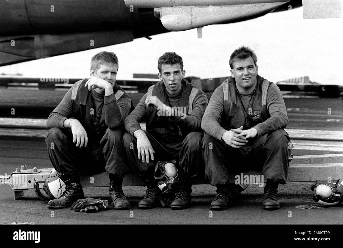 Three flight deck crewmen take advantage of a lull in flight operations ...