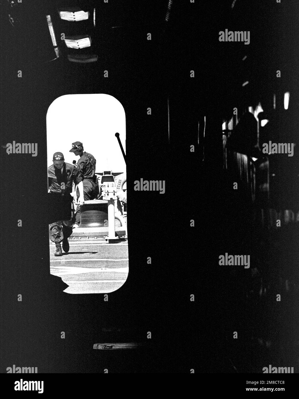 Crew members at work are framed by a hatch aboard the guided missile ...