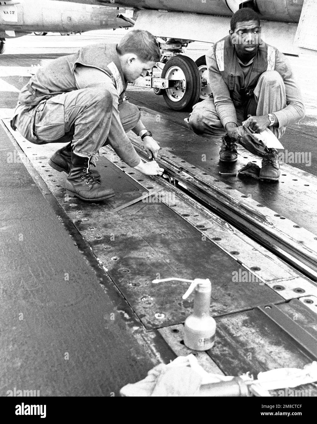 Two sailors check a catapult on the flight deck of the aircraft carrier ...