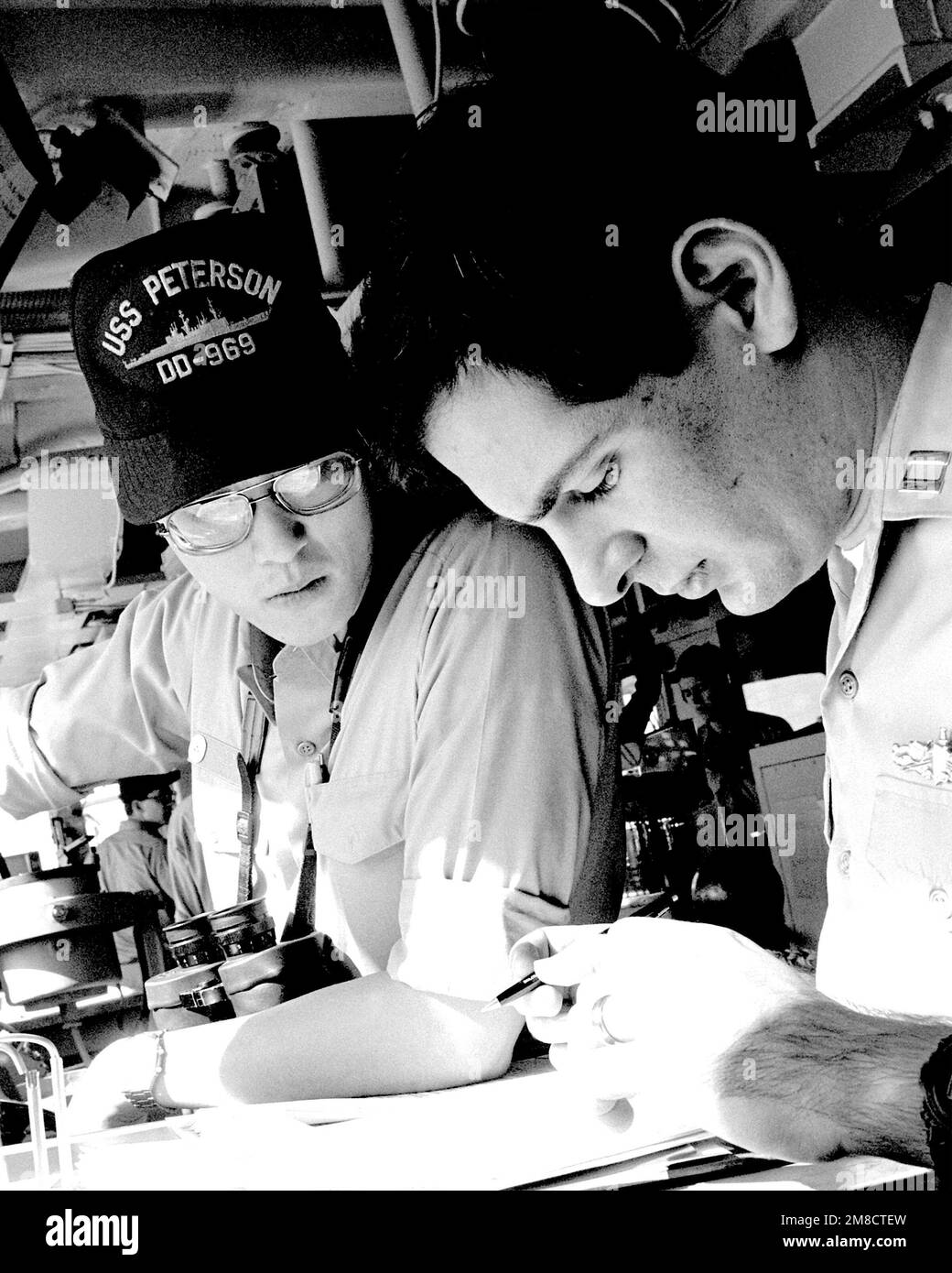 The officer of the deck and his relief confer in the pilot house aboard ...