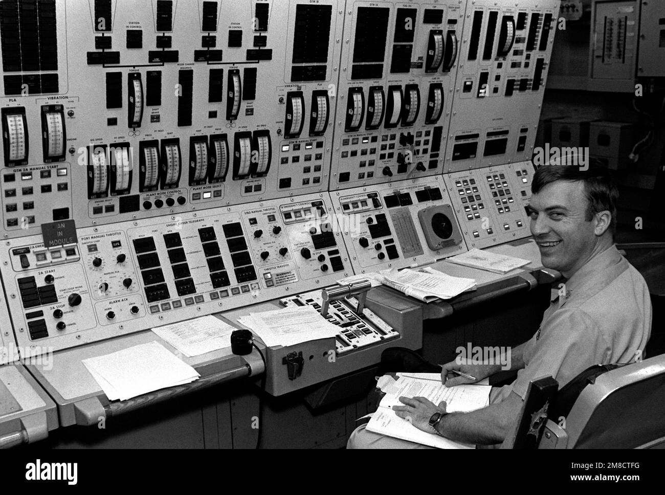 A crew member works at engine control panels in the central control ...