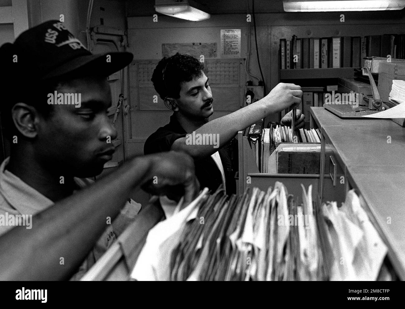 Crew members check files in the supply department aboard the destroyer ...