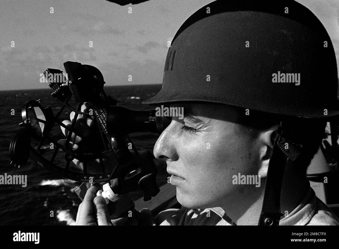A crew member of the destroyer USS PETERSON (DD 969) looks through a ...