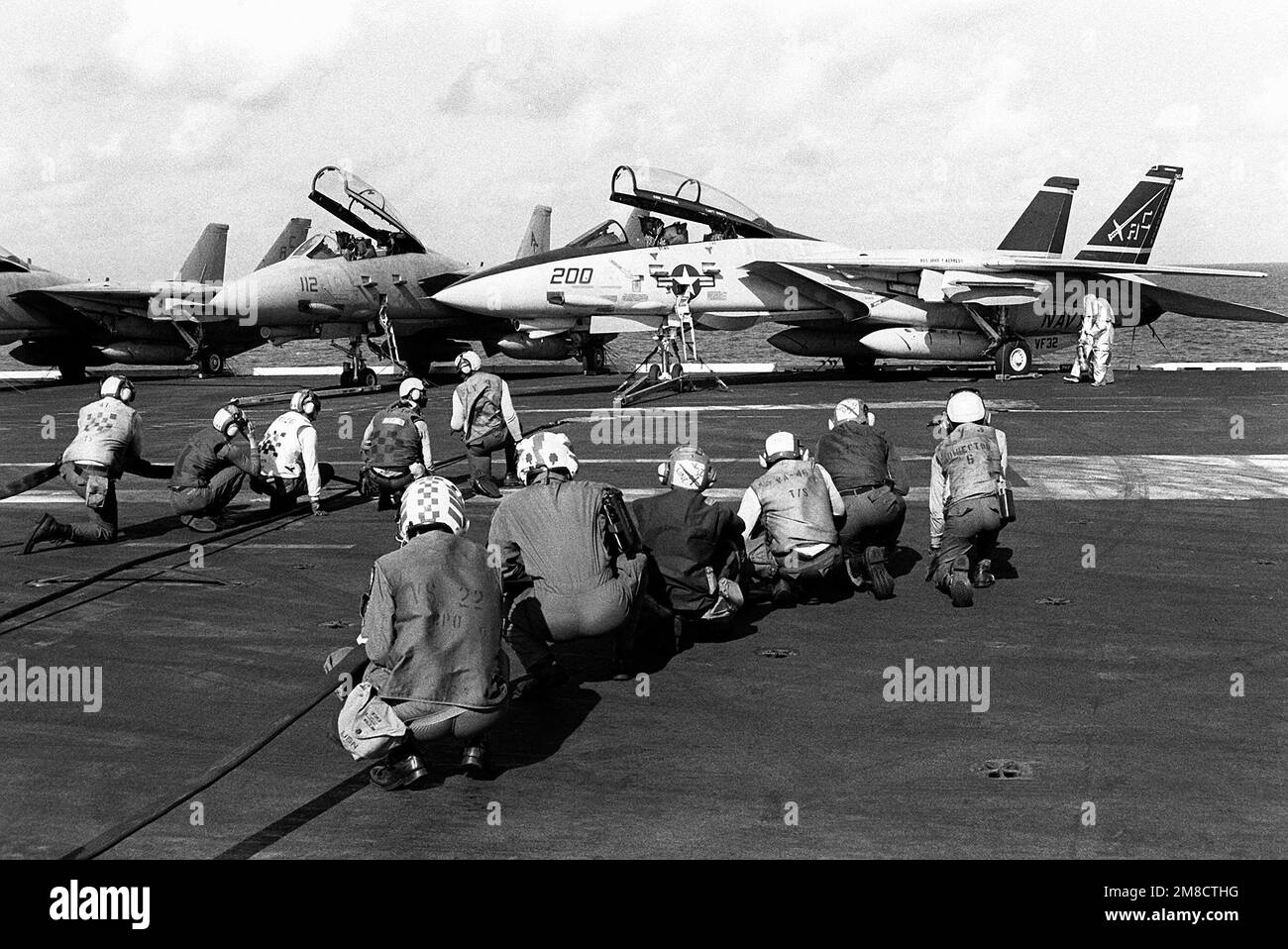 Hose teams take their positions on the flight deck of the aircraft ...