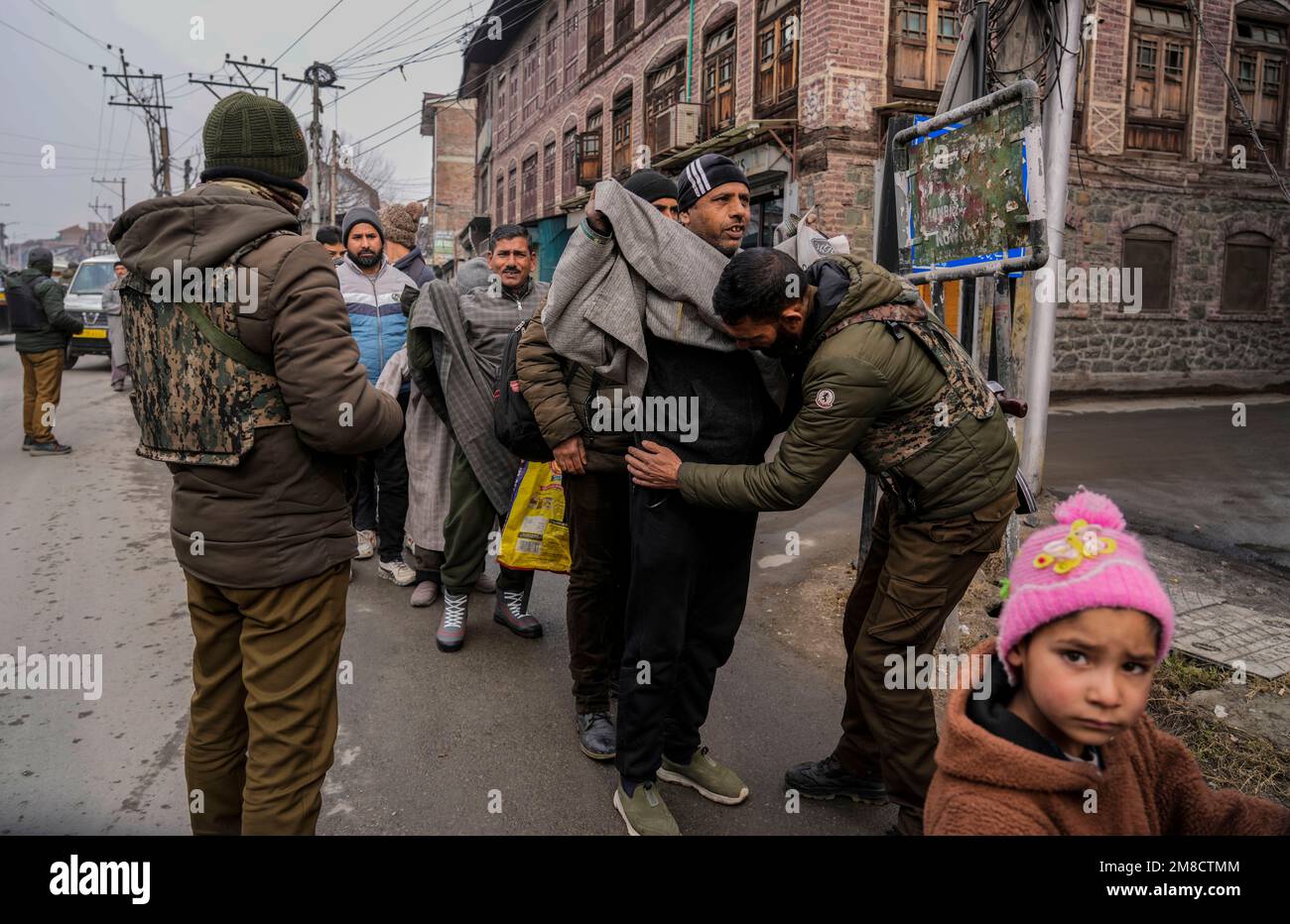 A child looks on as Indian policemen frisk Kashmiri pedestrians during ...