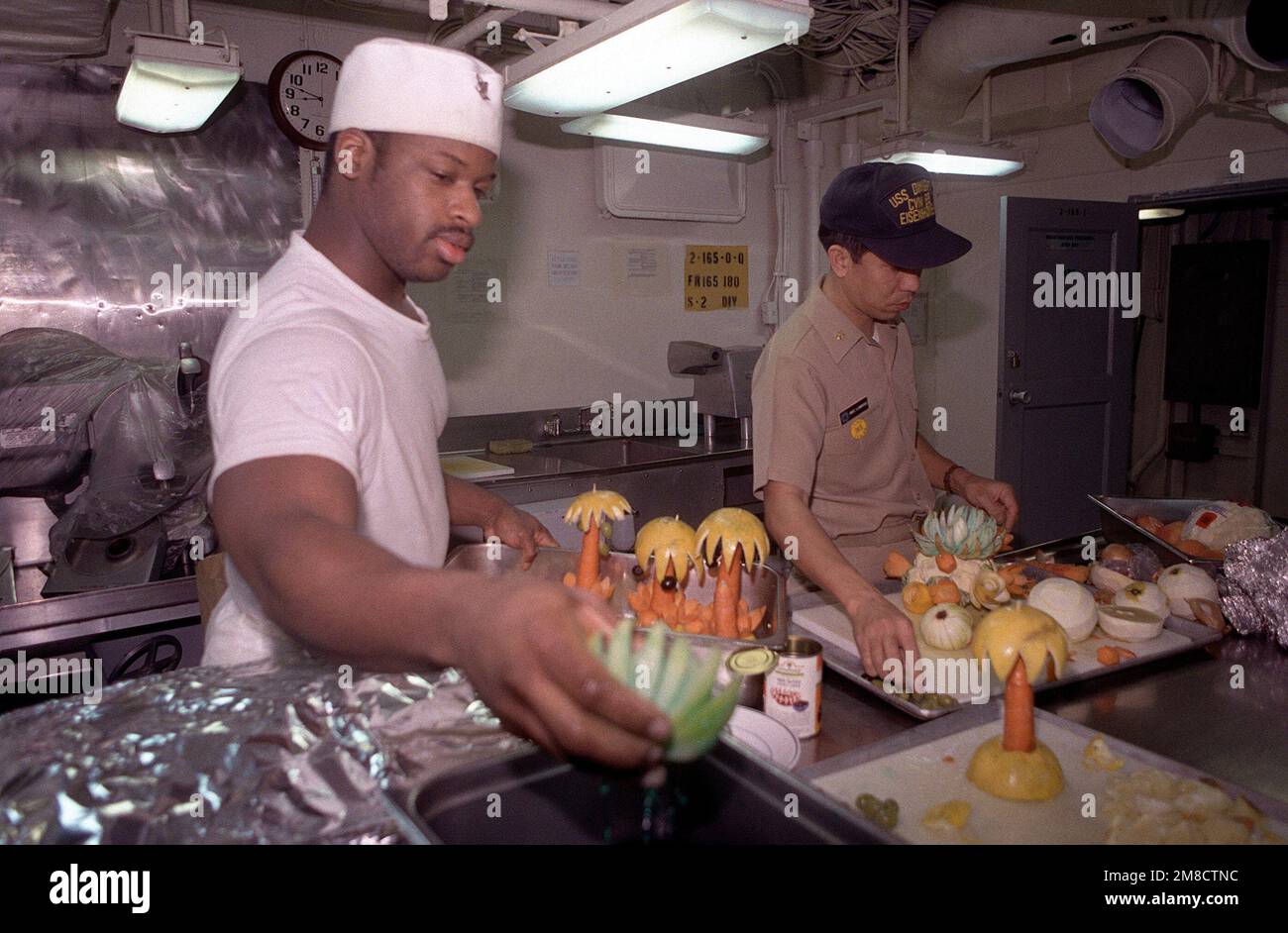 A chief mess management specialist helps a petty officer prepare ...
