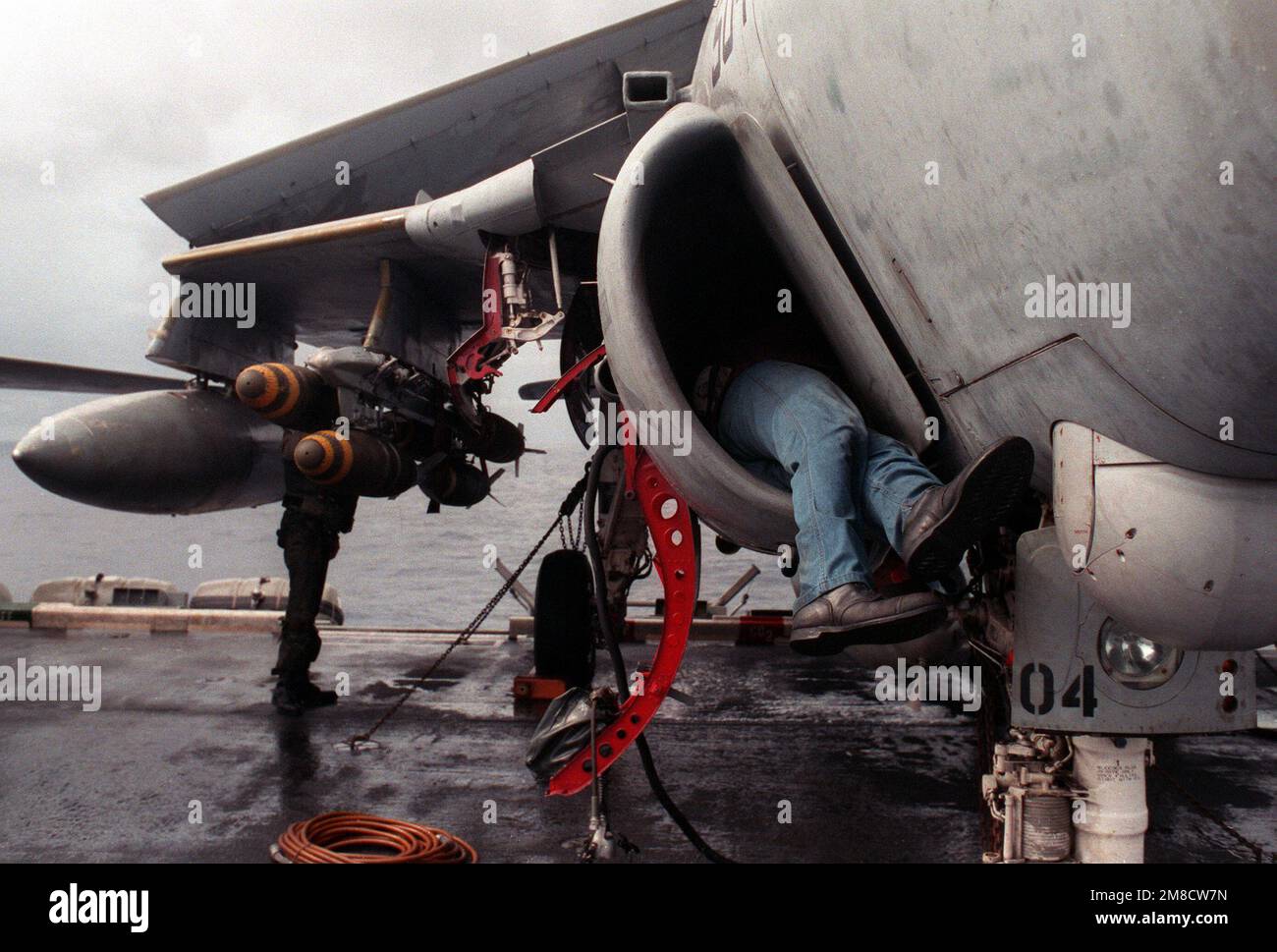 A squadron maintenance crewman inspects an engine intake as part of a ...