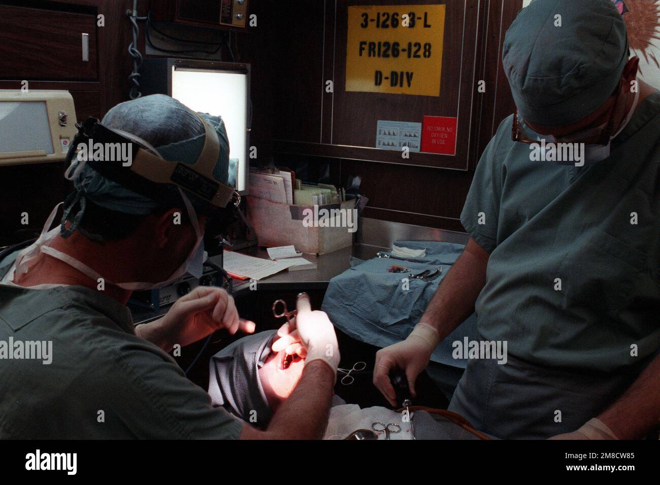 A dental officer and his assistant remove a sailor's wisdom teeth ...