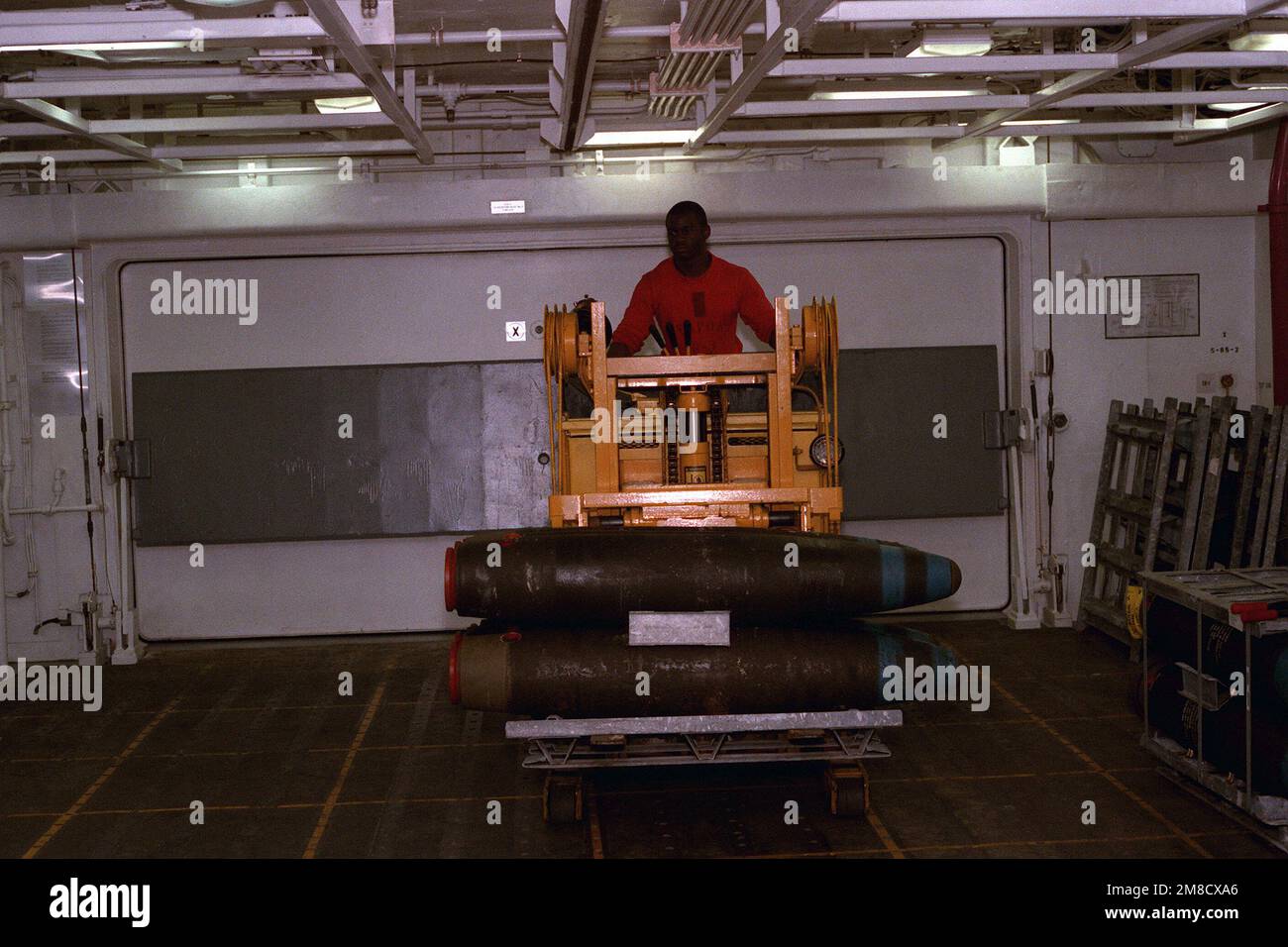 A crewman uses a forklift truck to move a pallet of BDU-45/B 500-pound ...