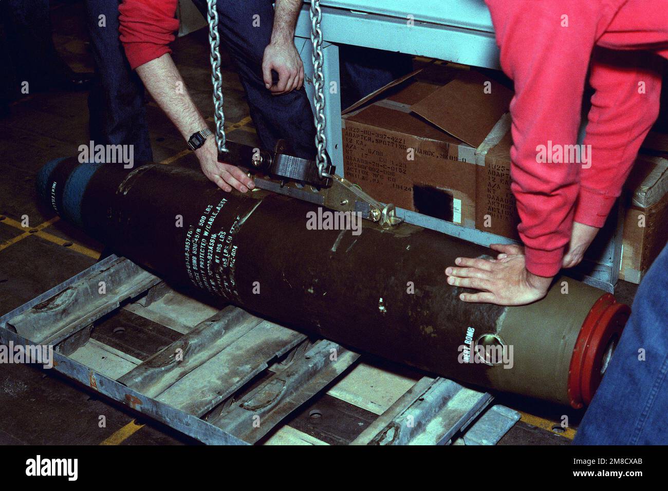 Lifting chains are attached to a BDU-45/B 500-pound practice bomb on a ...