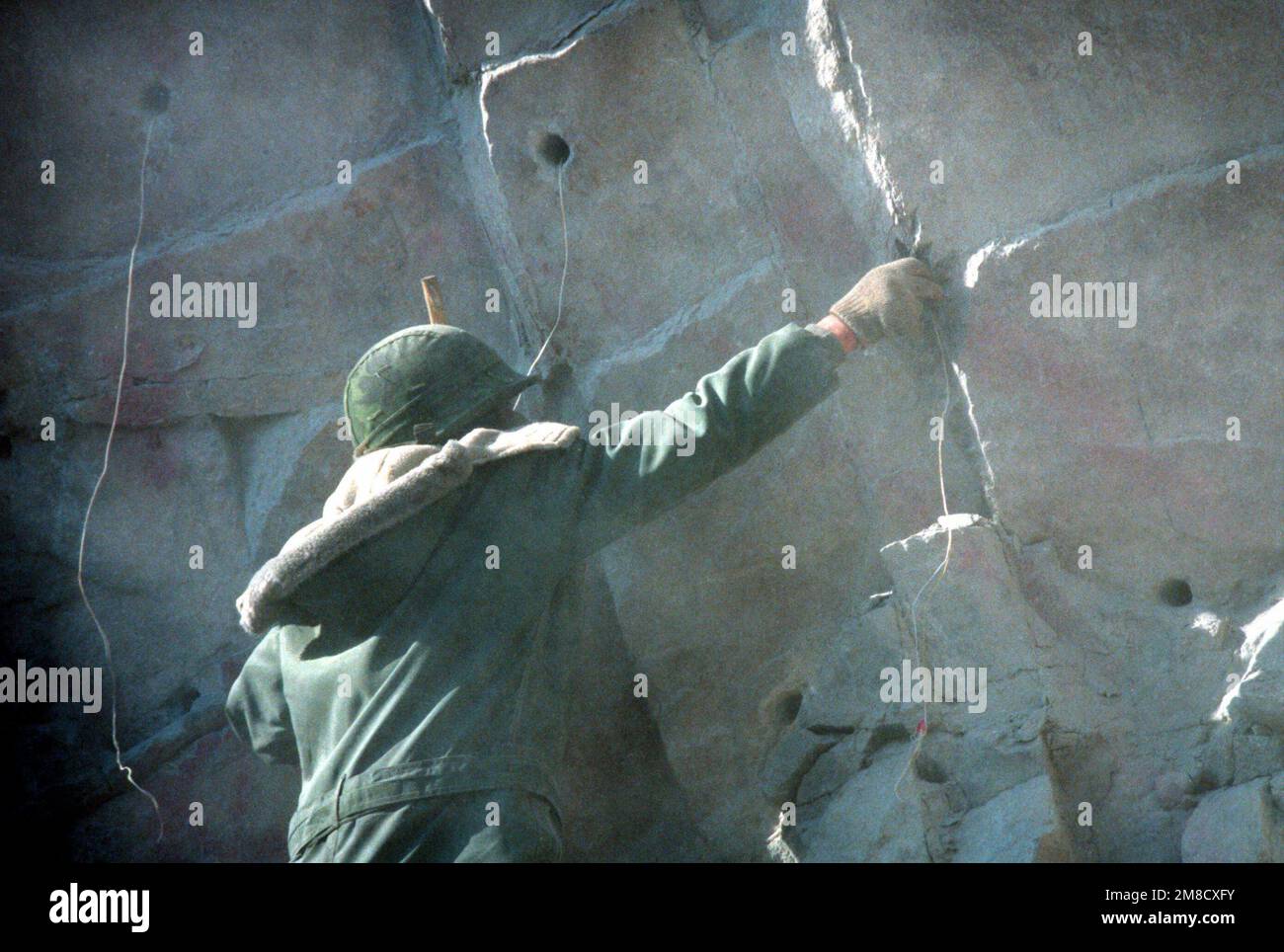 A worker sets explosive charges in the rock face prior to the arrival ...