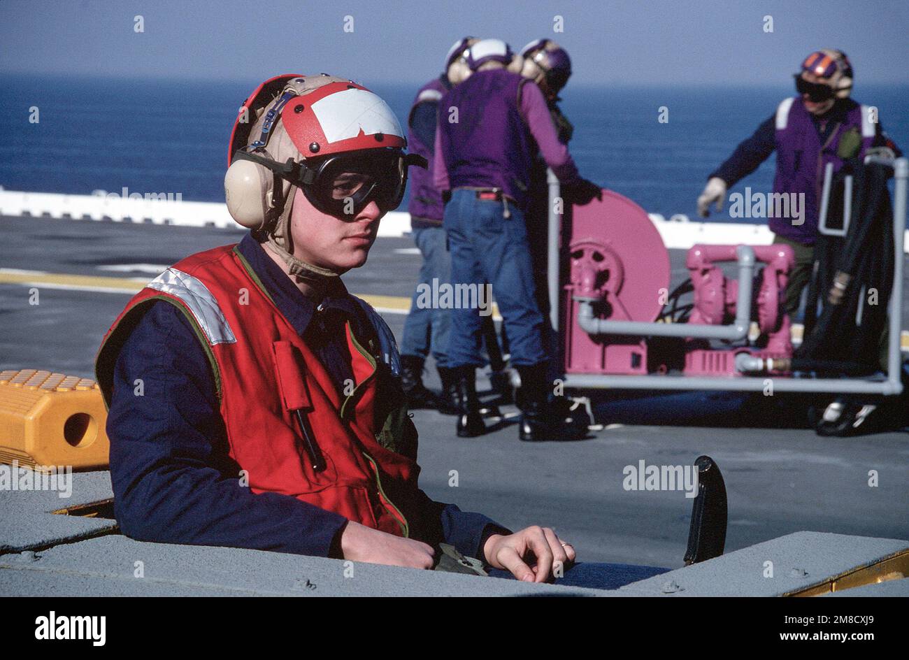 A flight deck crewman sits behind the wheel of an MD-3A tow tractor ...