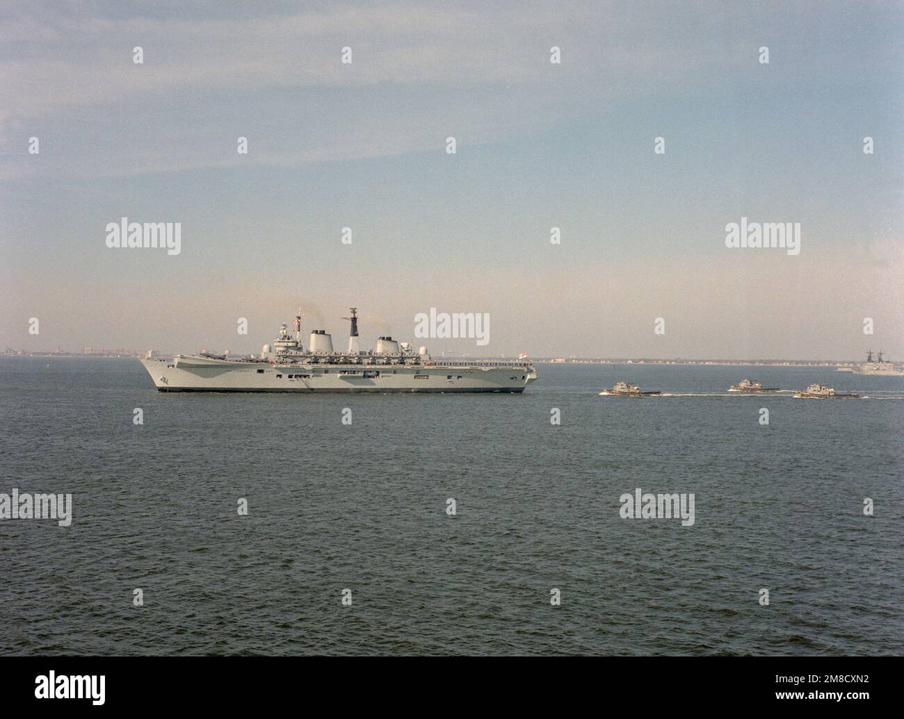 U.S. Navy large harbor tugs trail behind the British light aircraft ...