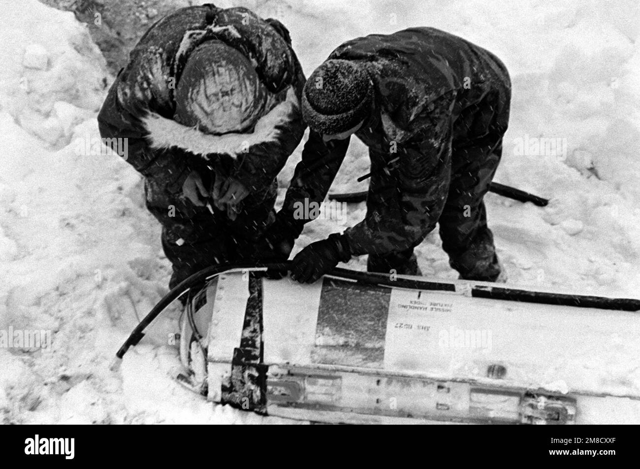 Two members of an explosive ordnance disposal (EOD) team place a line ...