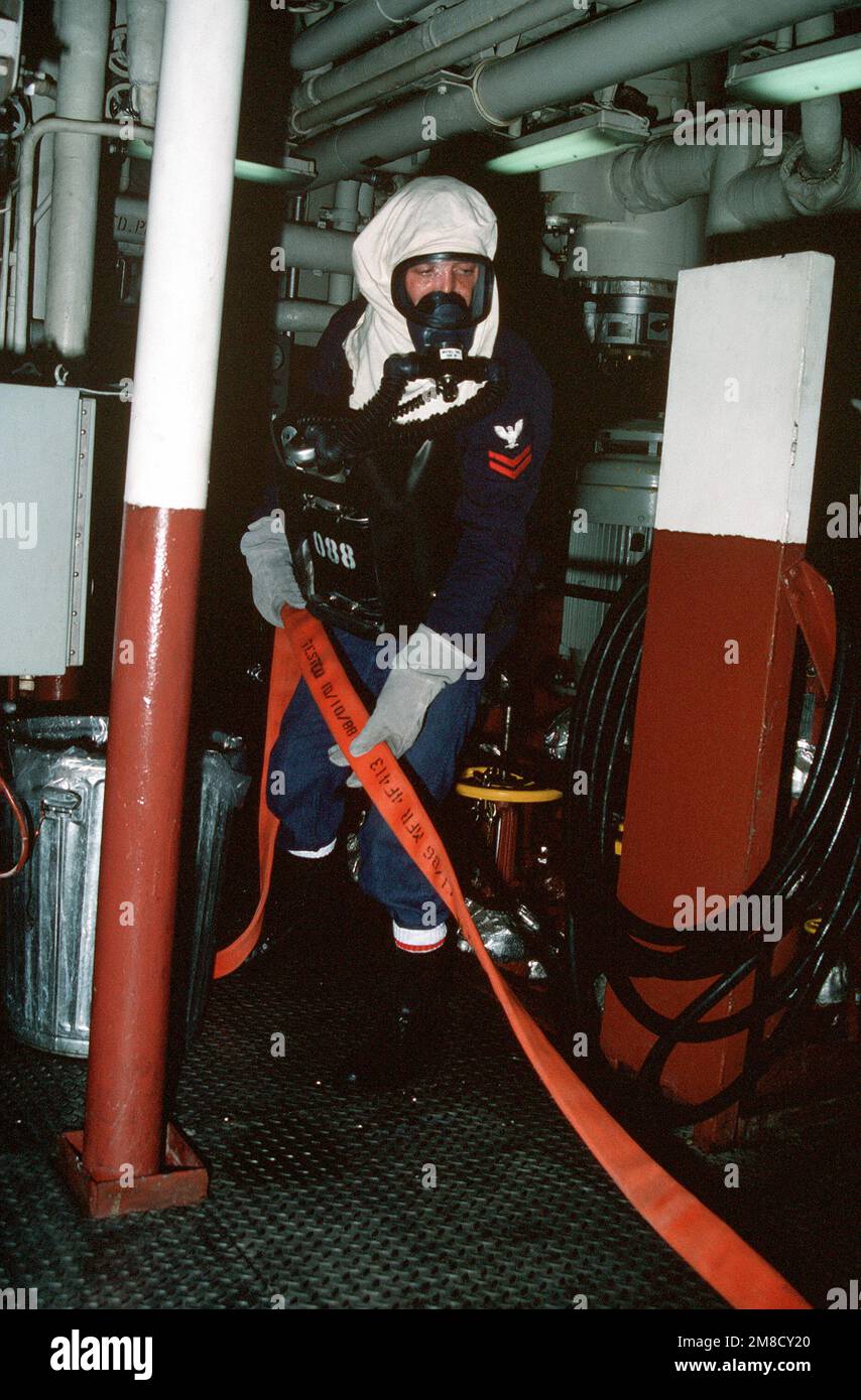A petty officer wearing an oxygen breathing apparatus (OBA) carries a ...