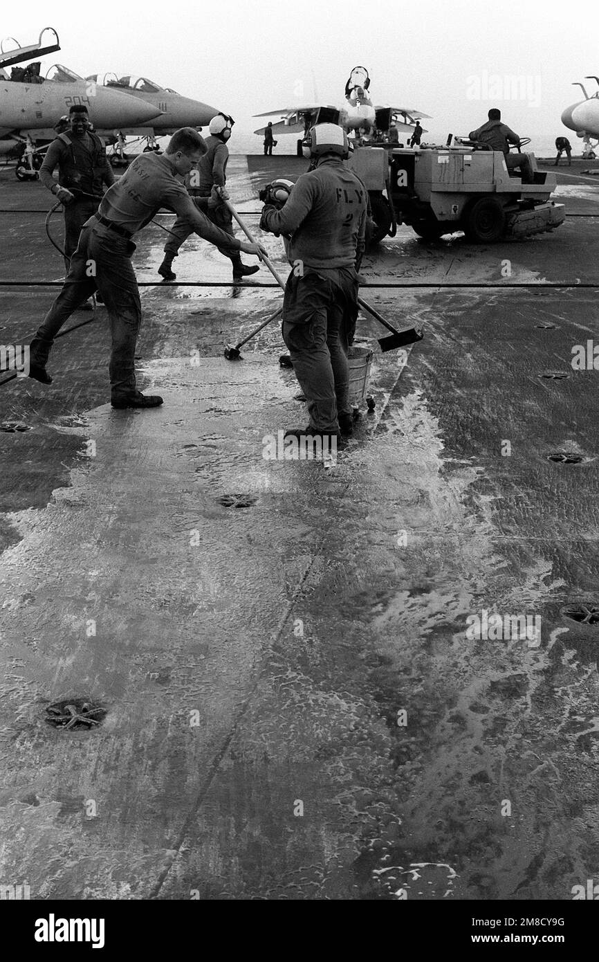 Crew members swab the flight deck of the aircraft carrier USS JOHN F ...