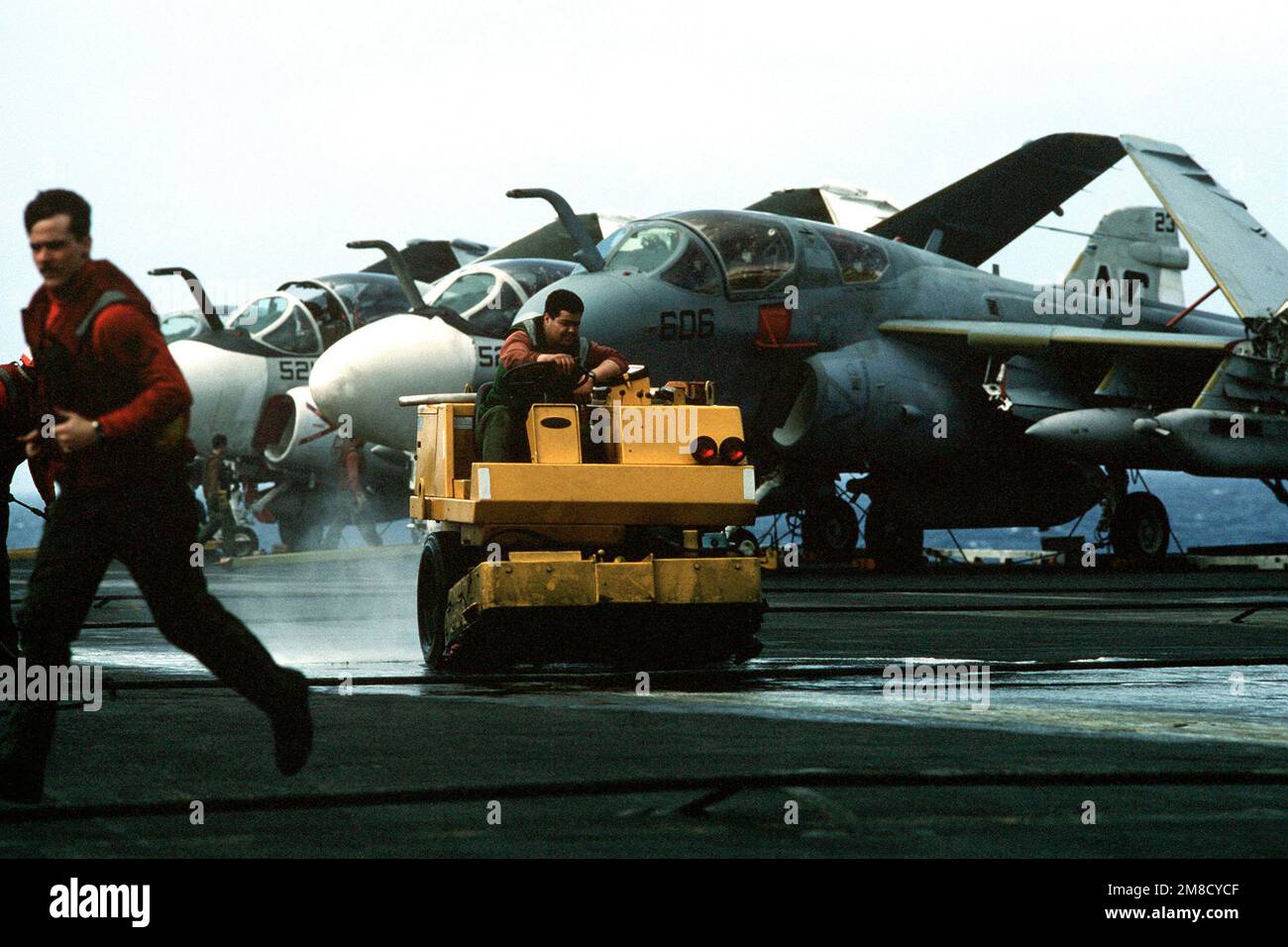 A crew member uses a scrubber truck to clean the flight deck of the ...