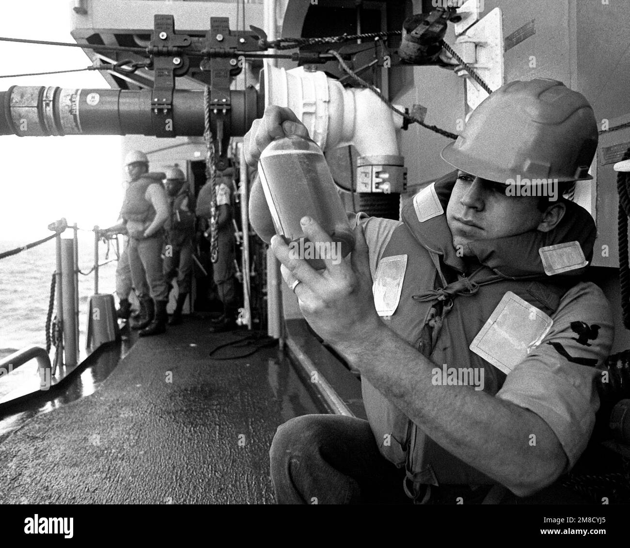 A crew member aboard the destroyer USS PETERSON (DD-969) inspects a ...
