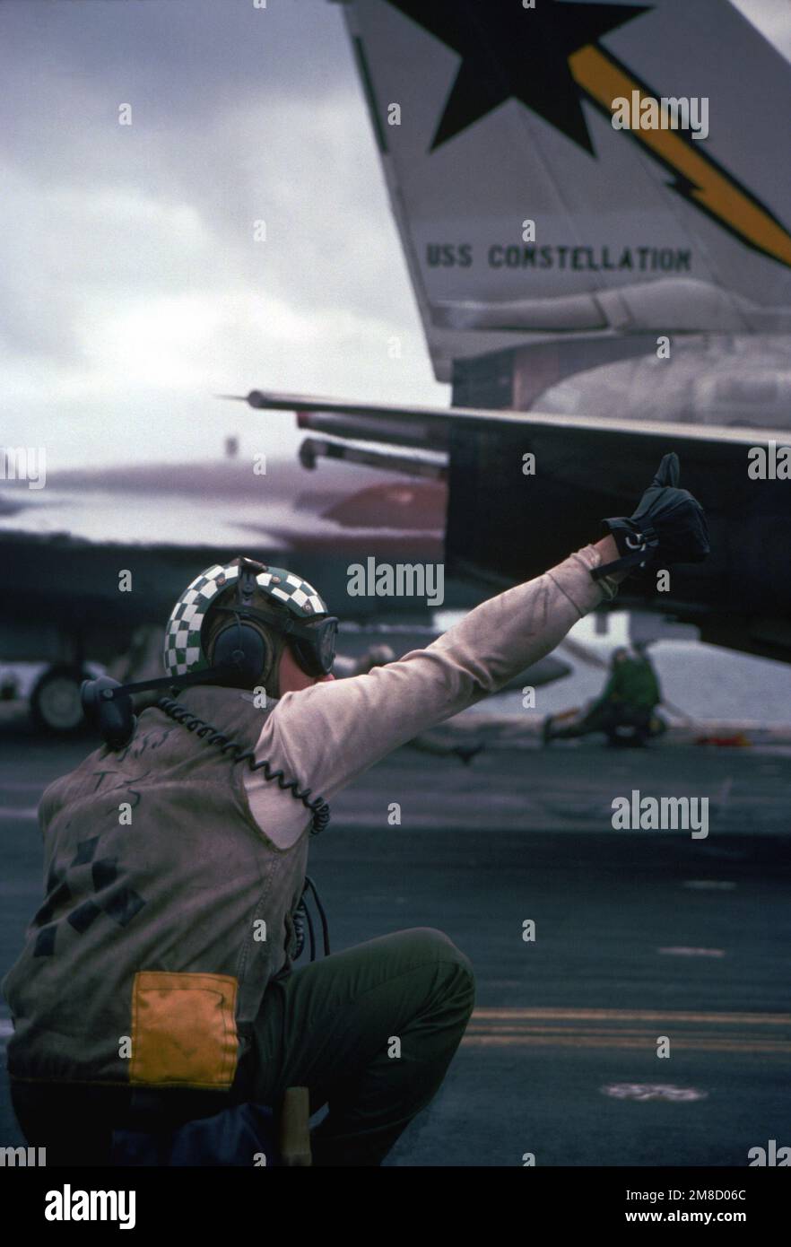 A safety checker signals to the catapult officer prior to the launch of ...