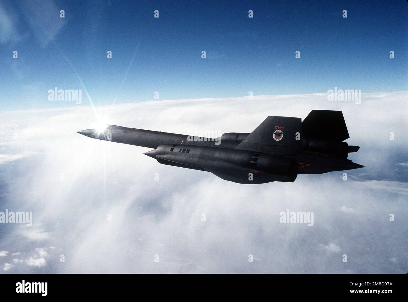 An air-to-air left side view of an SR-71 aircraft over cloud cover ...