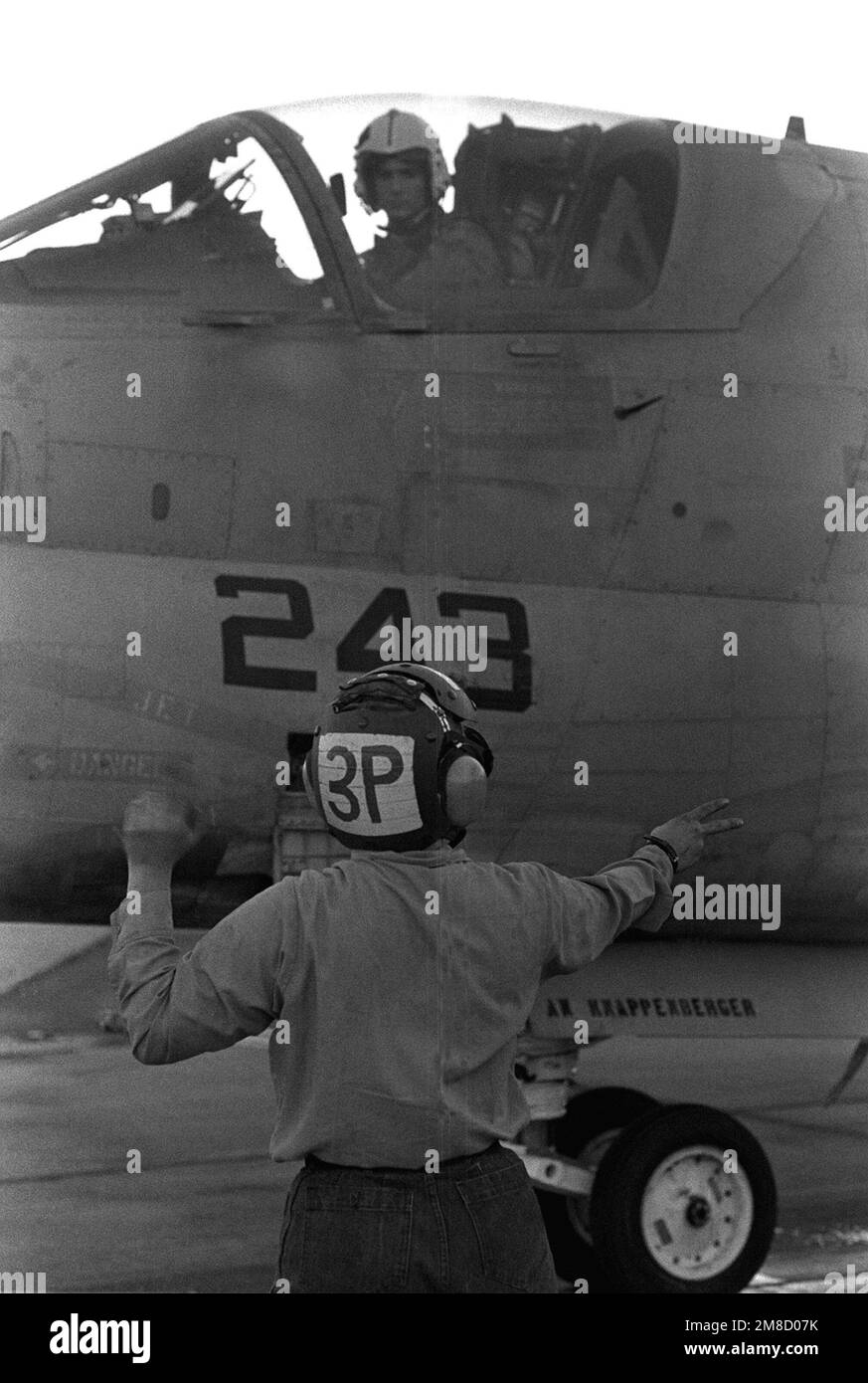 A plane director signals to the pilot of an Attack Squadron 122 (VA-122 ...