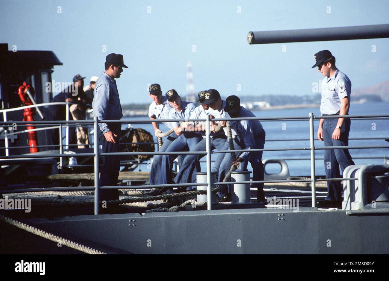 Sailors aboard the destroyer USS HEWITT (DD 966) haul in on a line as ...