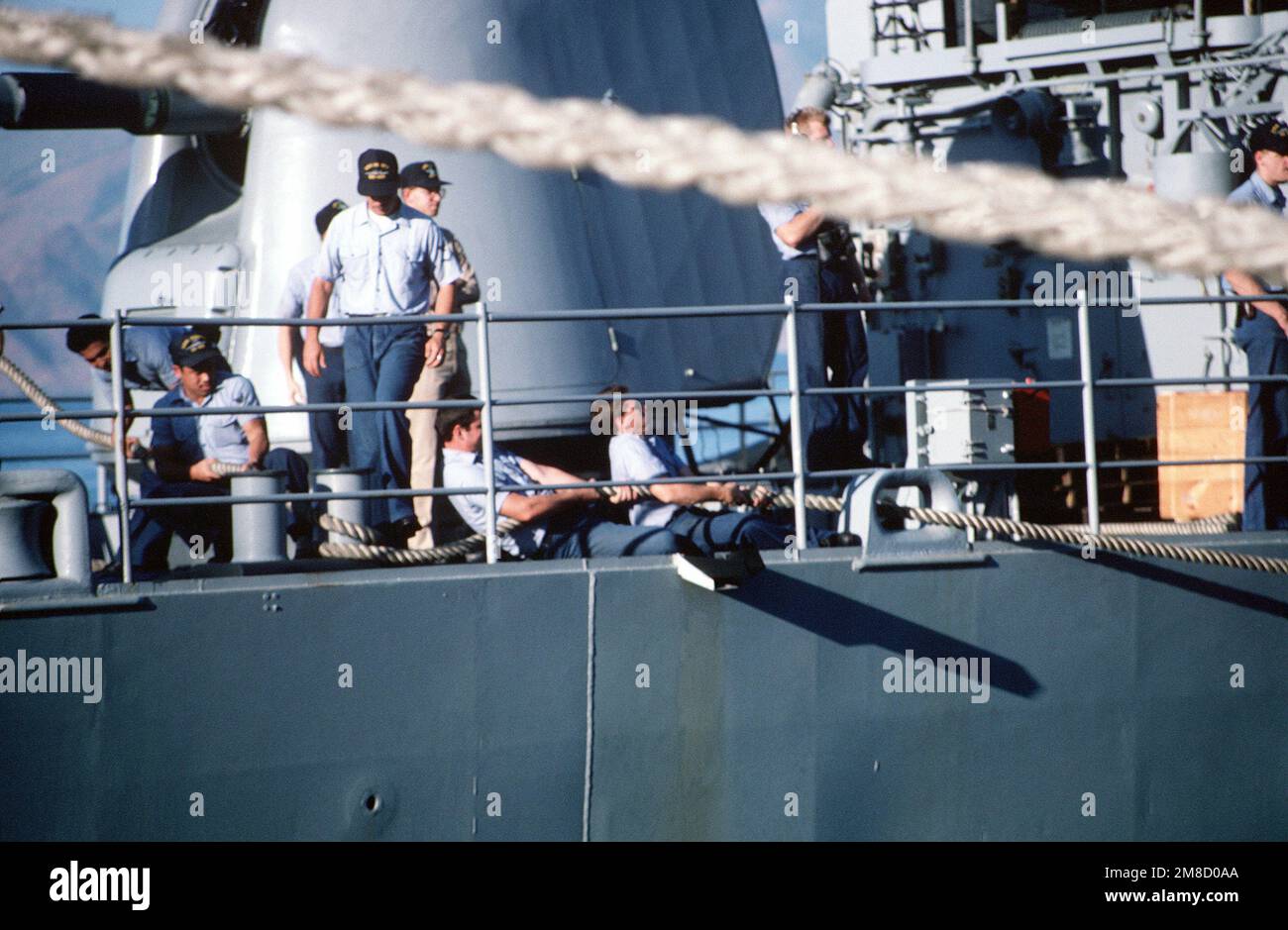 Sailors aboard the destroyer USS HEWITT (DD 966) haul in on a line as ...